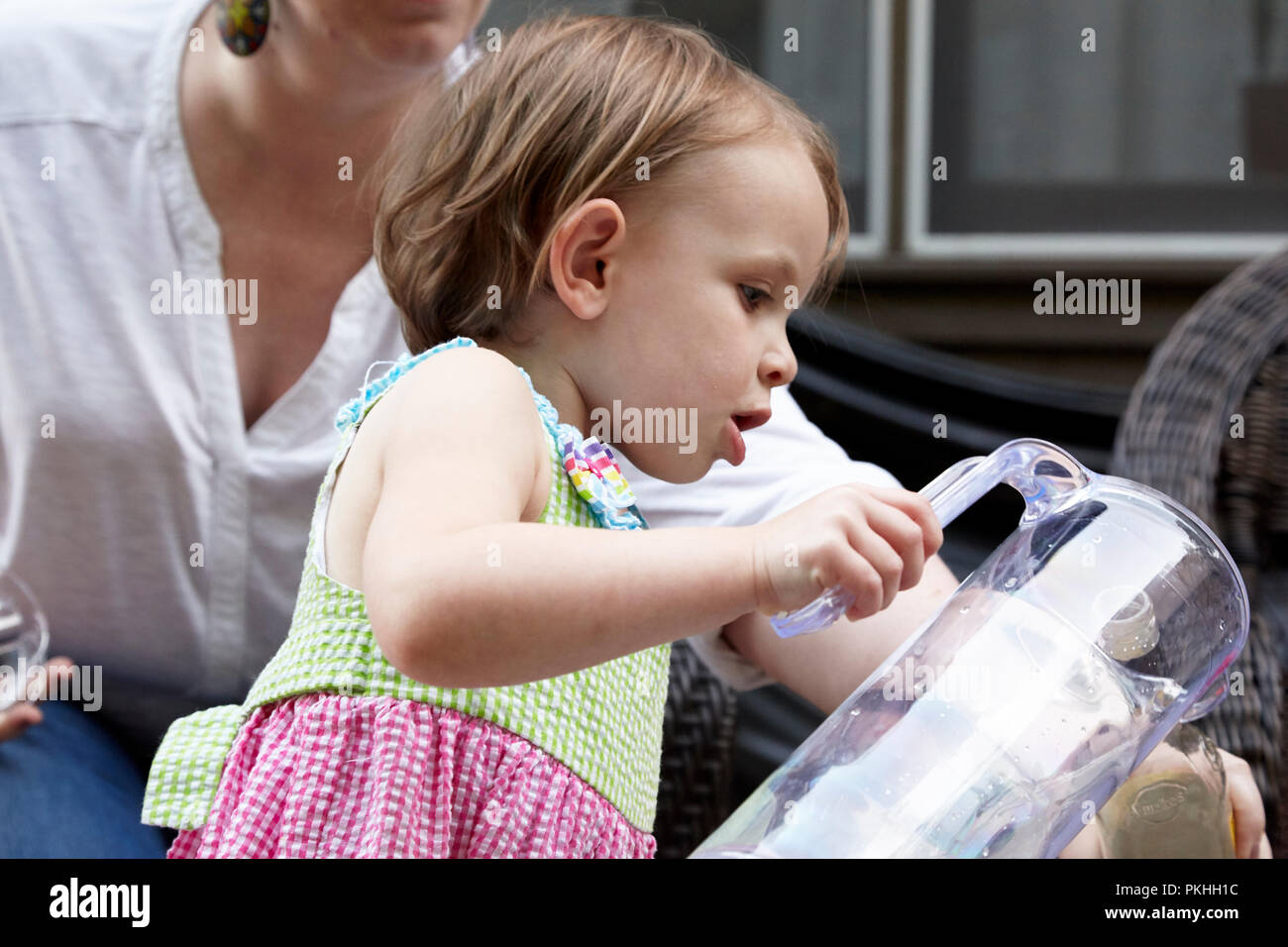 little girl pouring water with moms help Stock Photo - Alamy