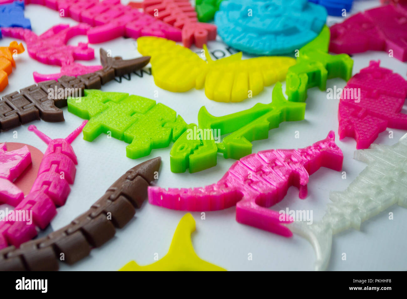 Many bright multi-colored objects printed on 3d printer lie on flat ...