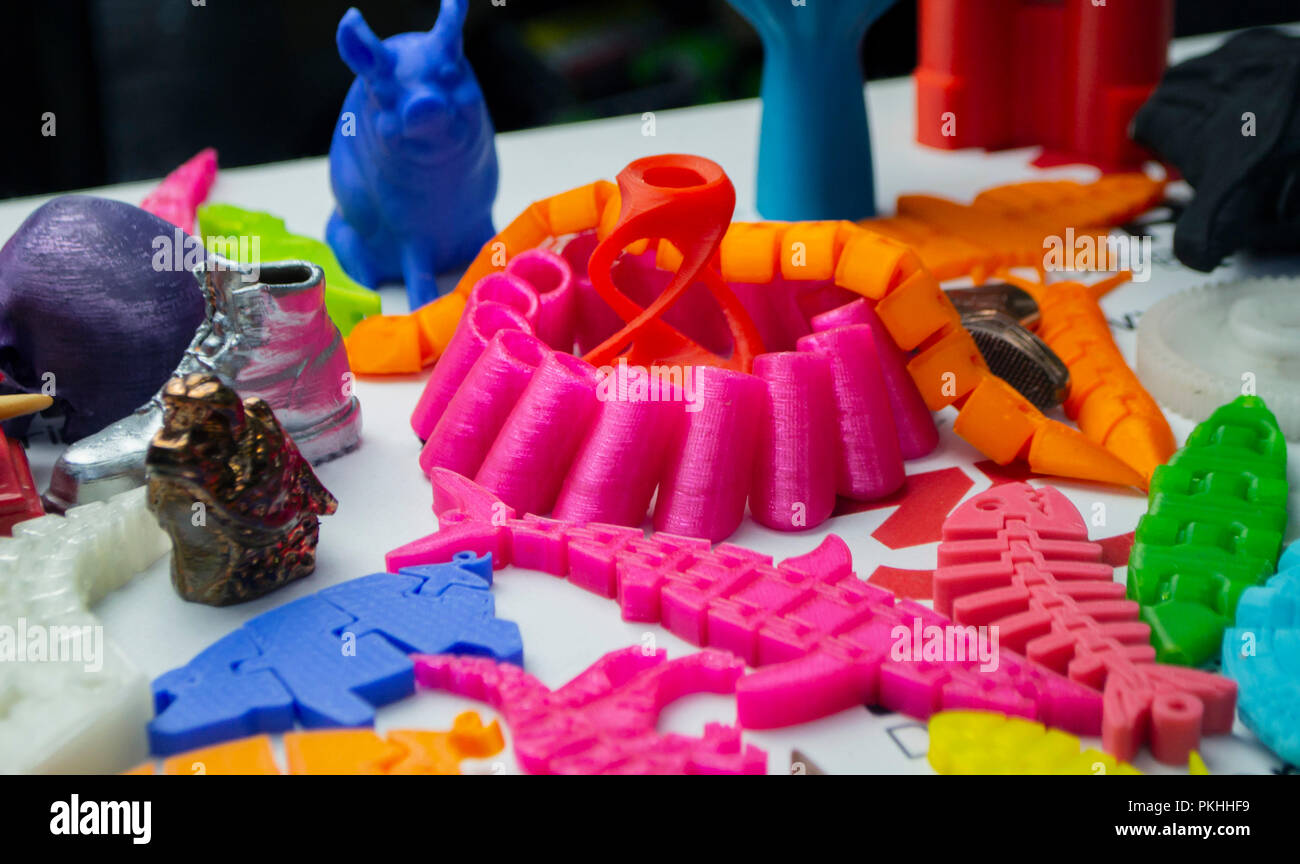 Many bright multi-colored objects printed on 3d printer lie on flat ...