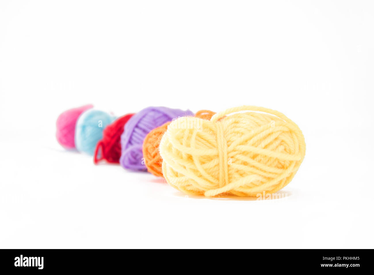 A row of colored yarn balls in a row on a white background Stock Photo ...