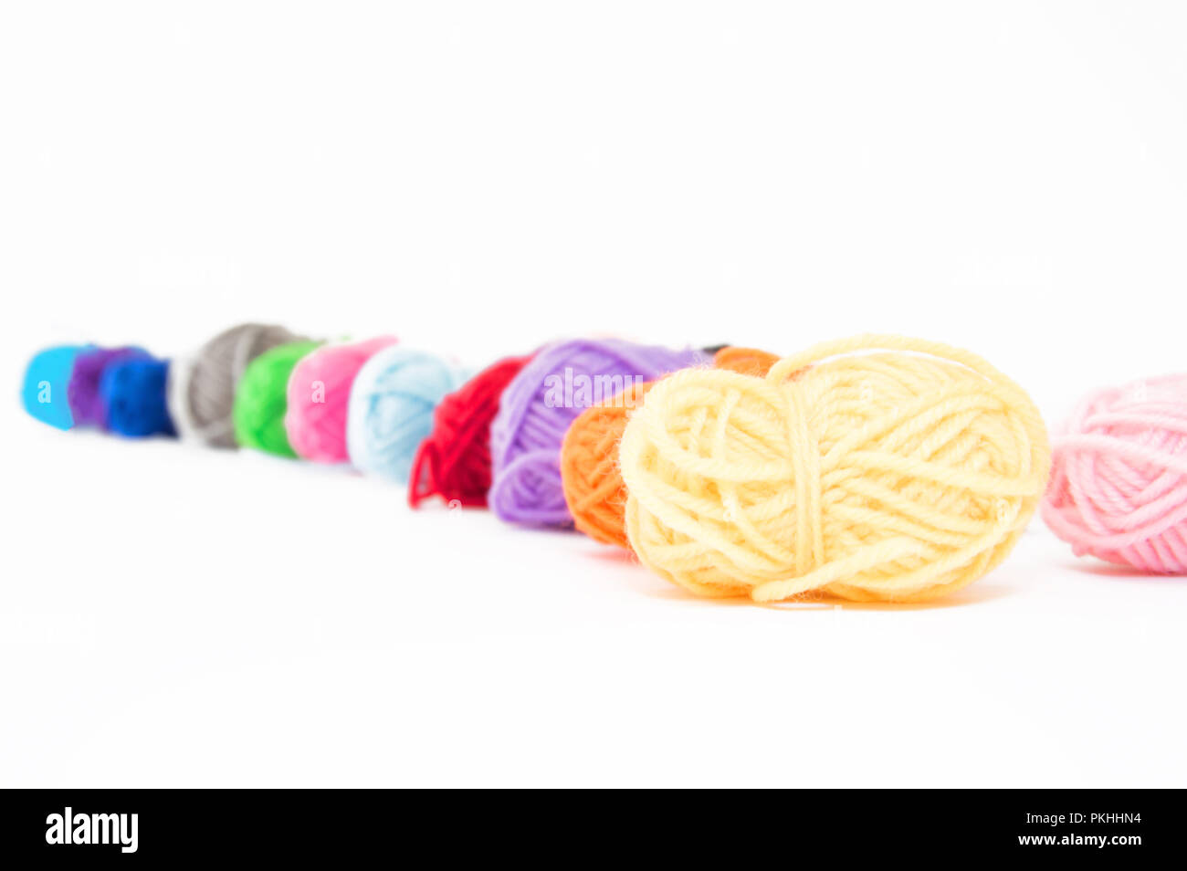 A row of colored yarn balls in a row on a white background Stock Photo ...