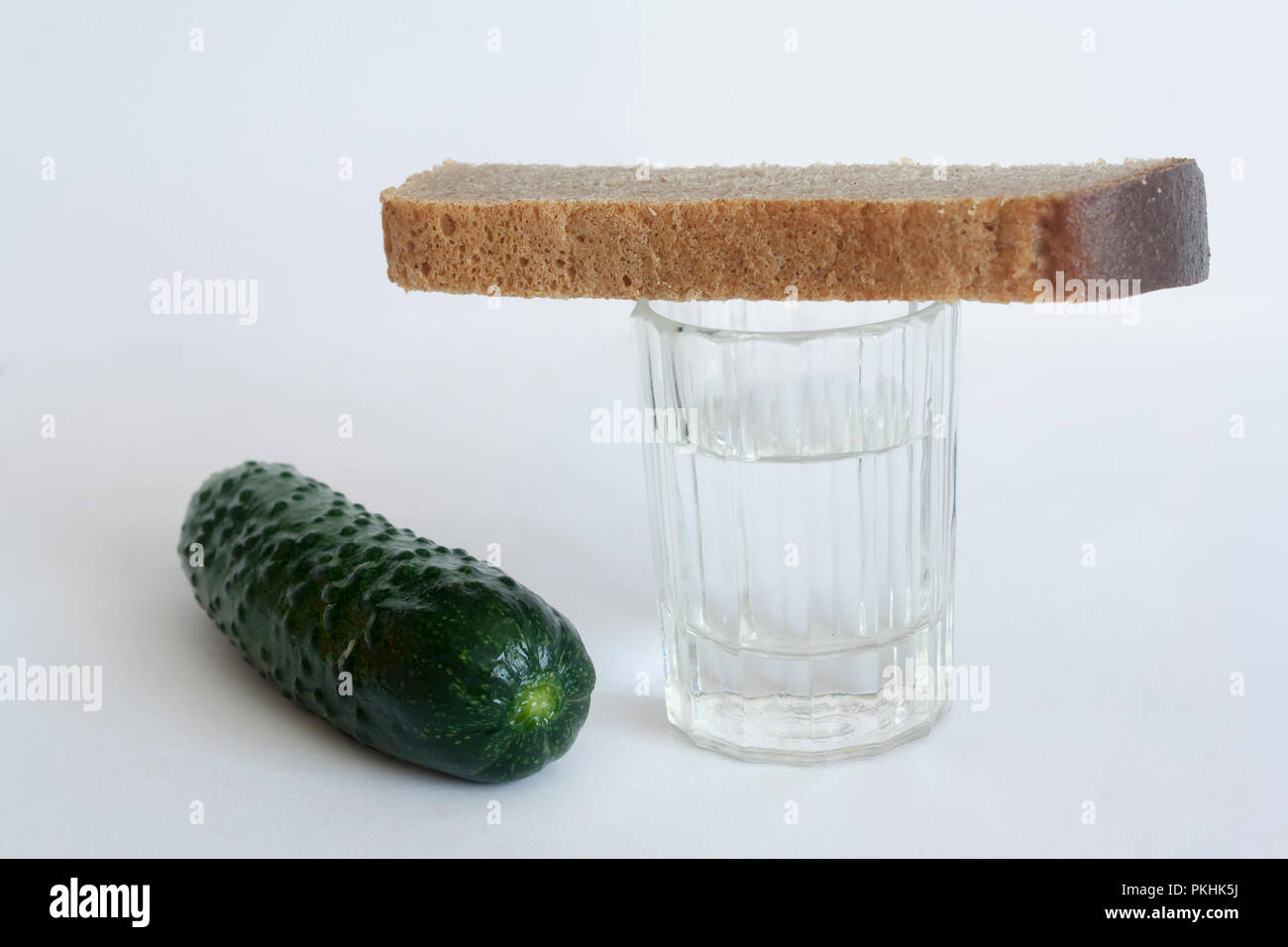 a stack of vodka, bread and salted cucumber on white background Stock ...