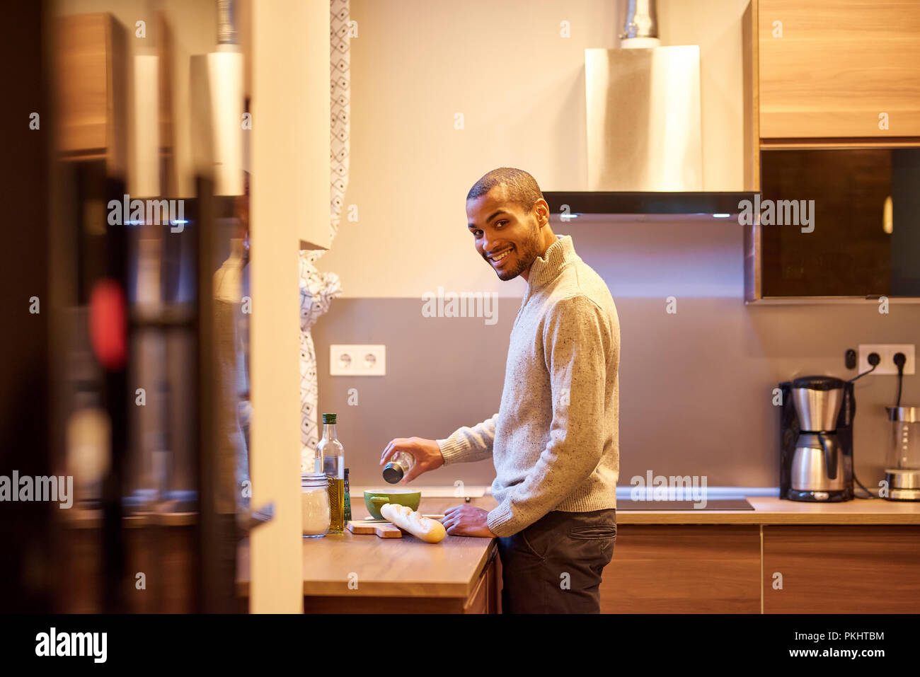 A happy handsome young man cooking in the kitchen in a sweater Stock ...