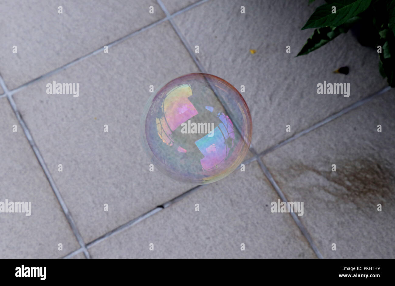A big bubble mirroring sky and roof. Bubble flying above pavement ...