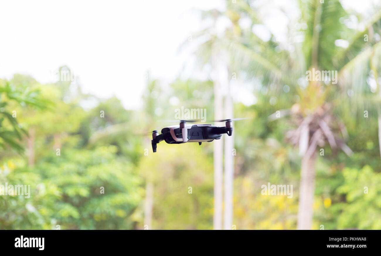 Small grey drone quadcopter flying near green trees daytime Stock Photo ...