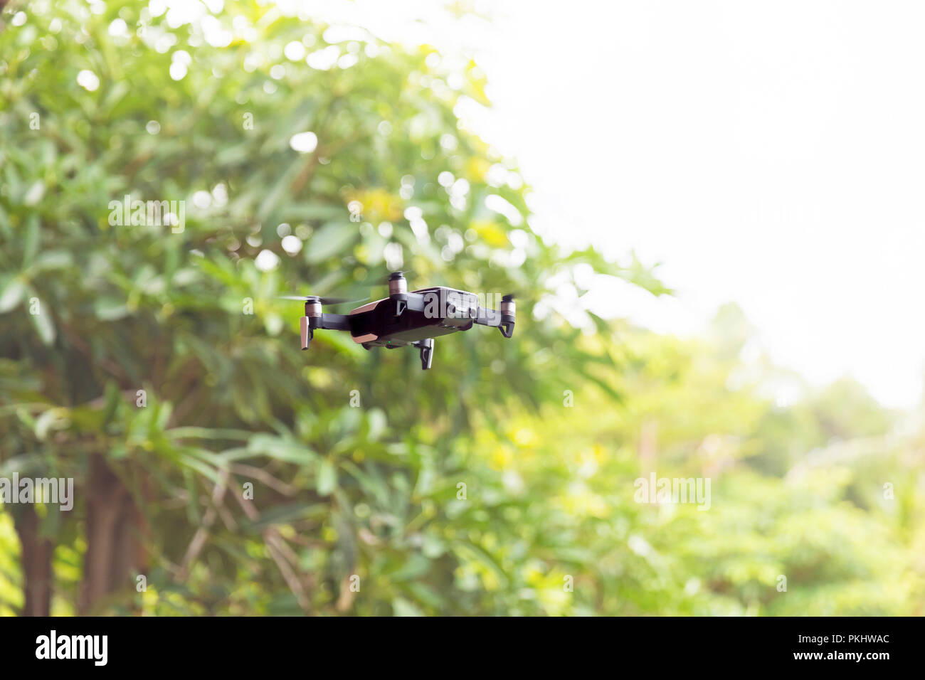 Small grey drone quadcopter flying near green trees daytime Stock Photo ...