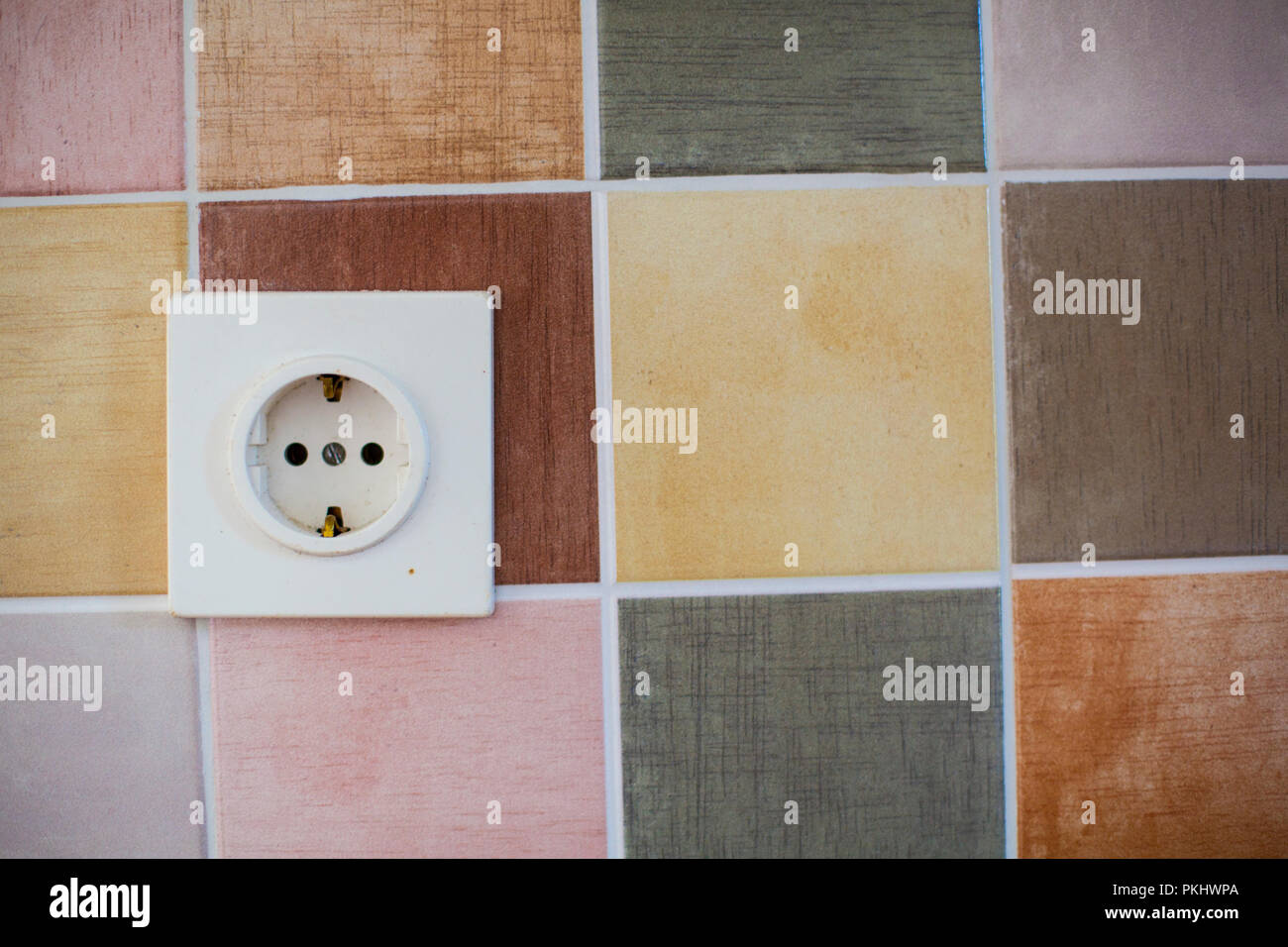 Electrical outlet on the wall with colored tiles Stock Photo - Alamy