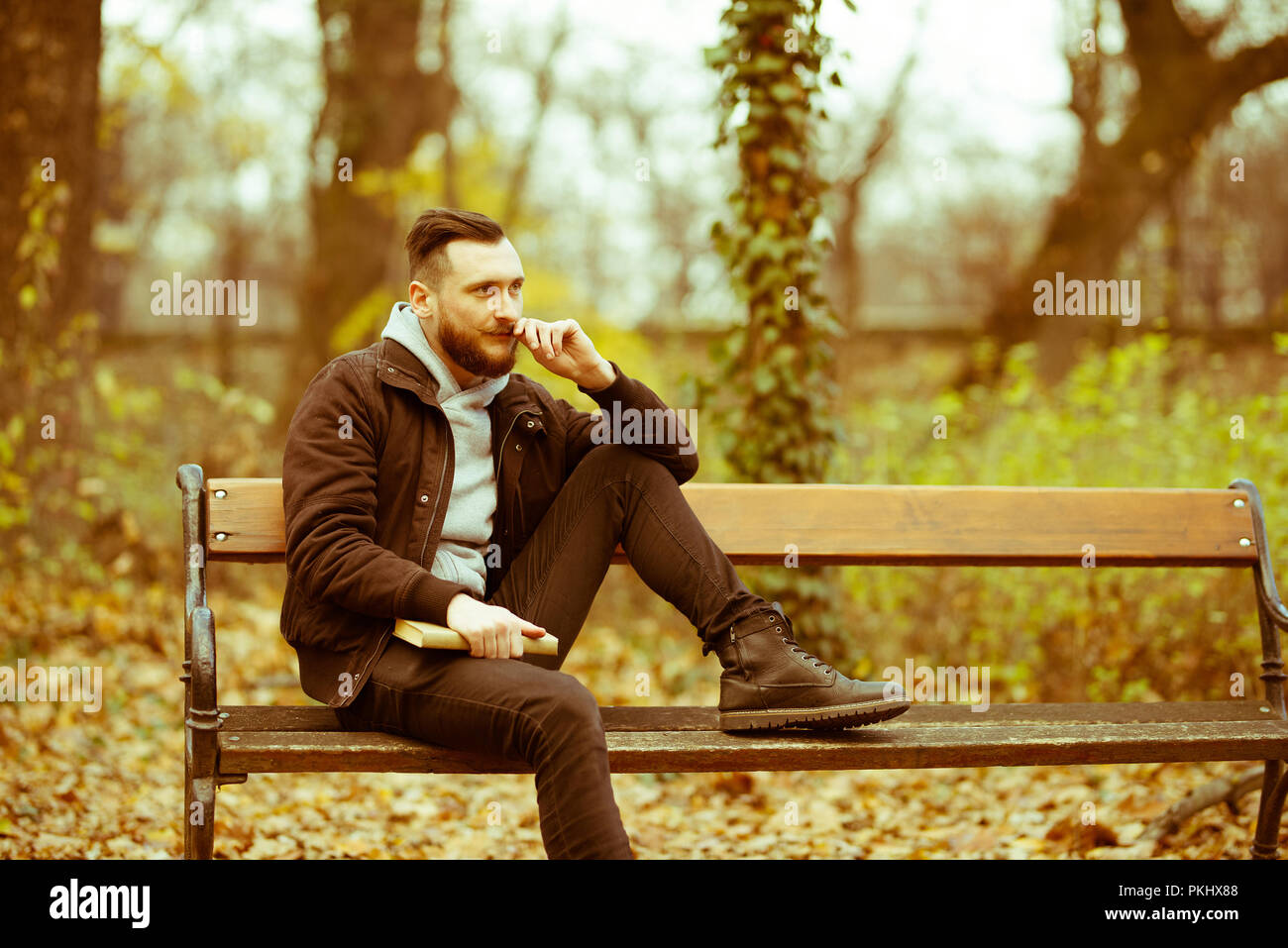 A retro style photo of a young hipster man sitting on a bench and ...