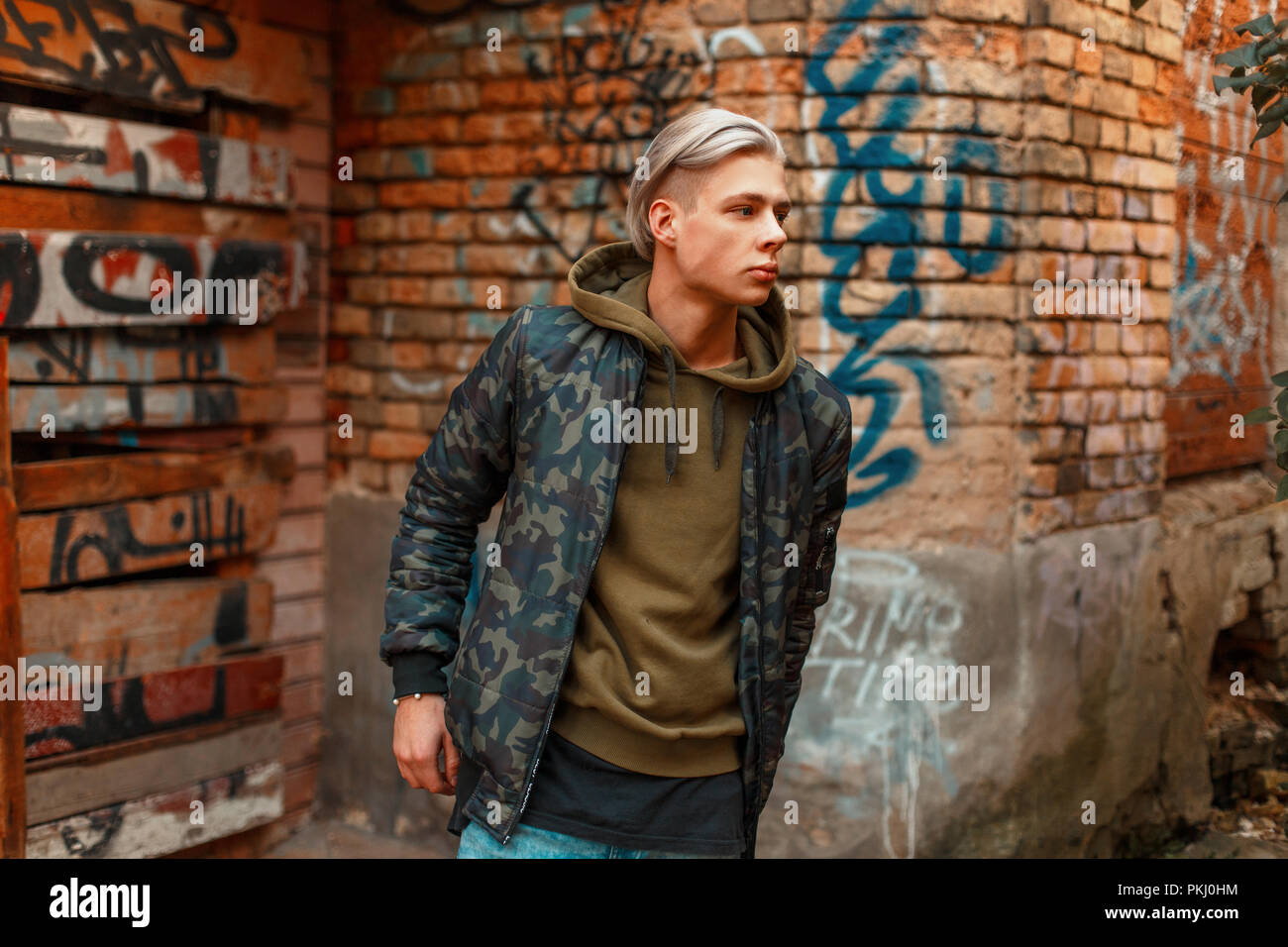 Fashion handsome male model in military jacket near wall Stock Photo ...