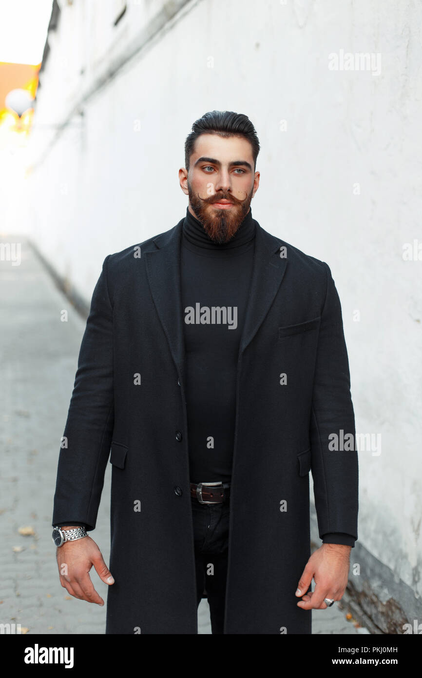 Handsome hipster man with a beard in a black coat on the street Stock ...