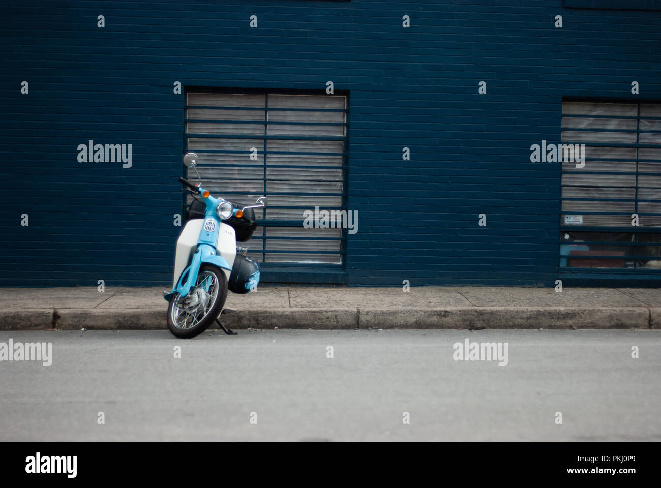 Blue scooter parked in front of a blue wall Stock Photo - Alamy