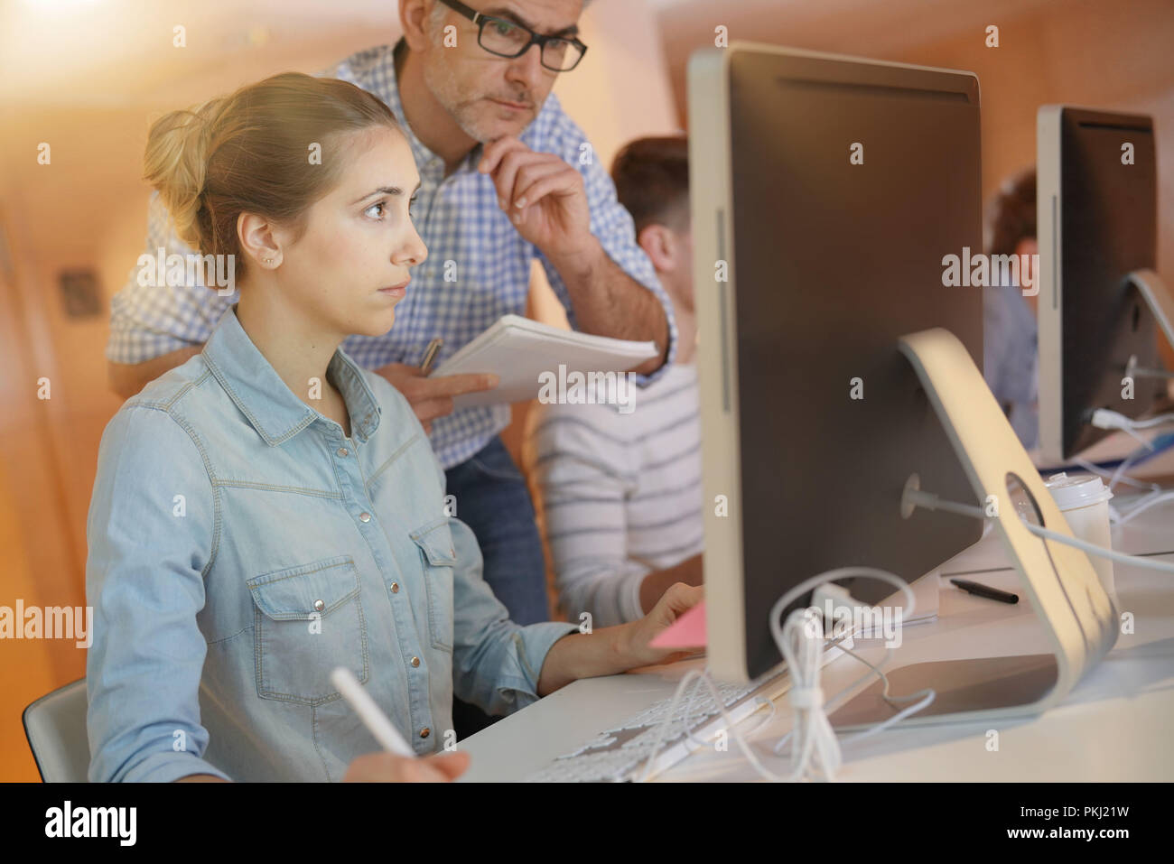 Teacher with student working on desktop computer Stock Photo - Alamy