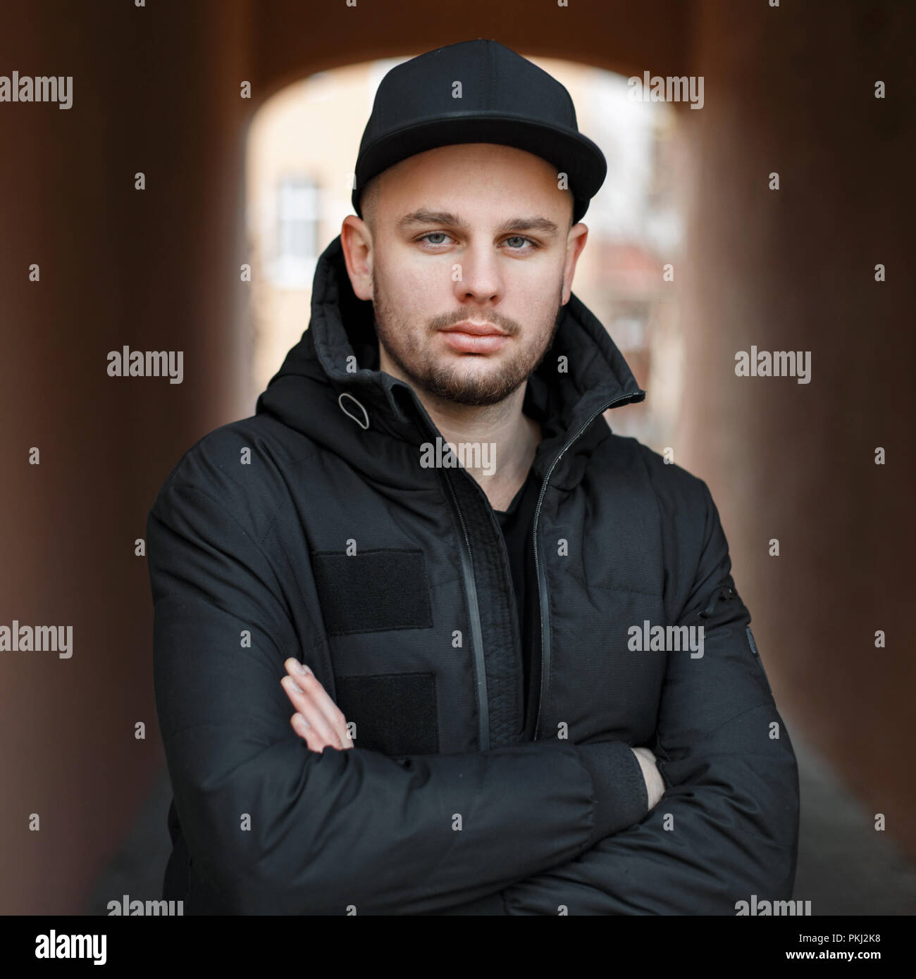 Handsome stylish man in a black baseball cap and winter jacket posing ...