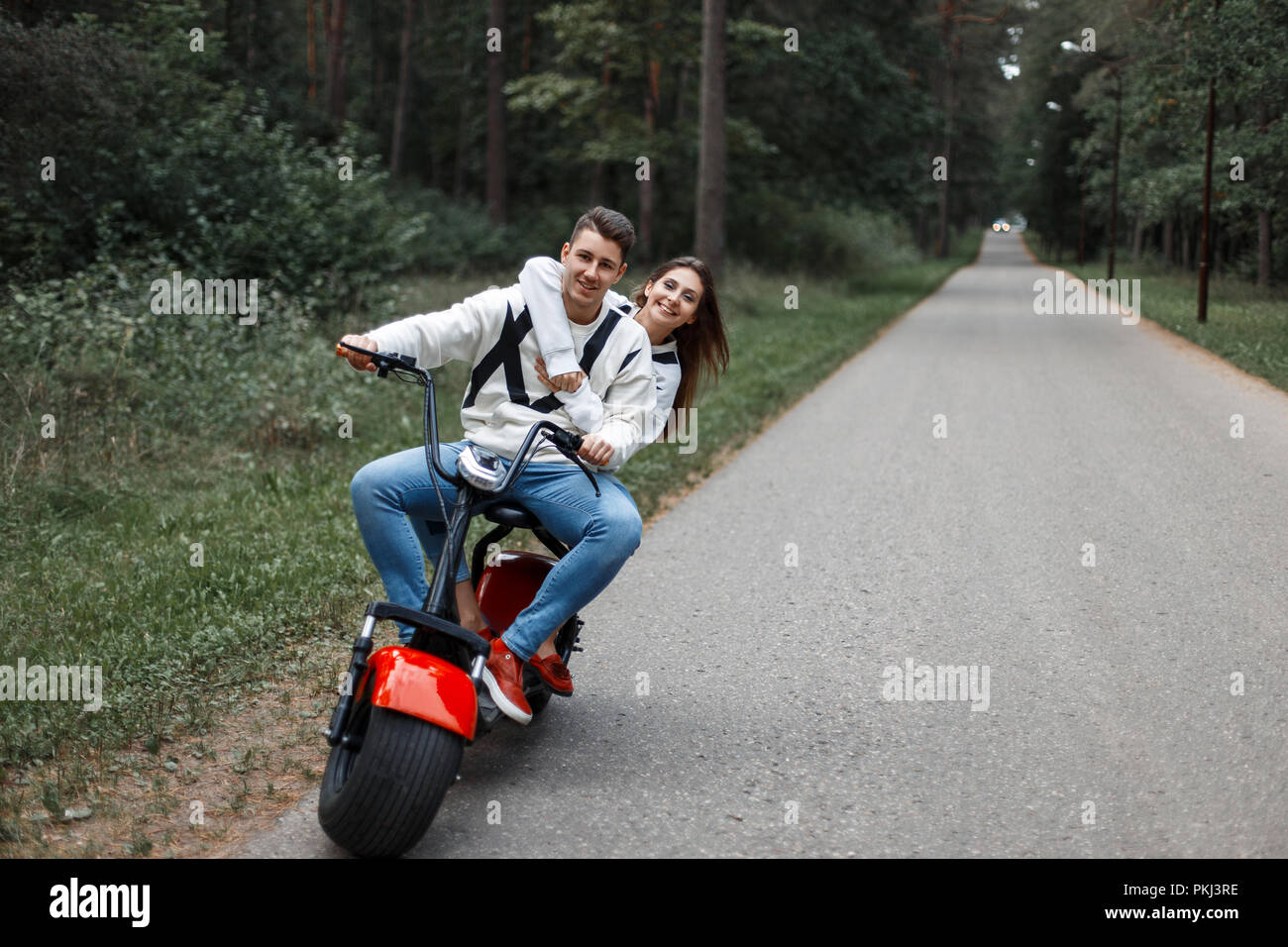 Couple in love riding an electric bike on the road Stock Photo - Alamy