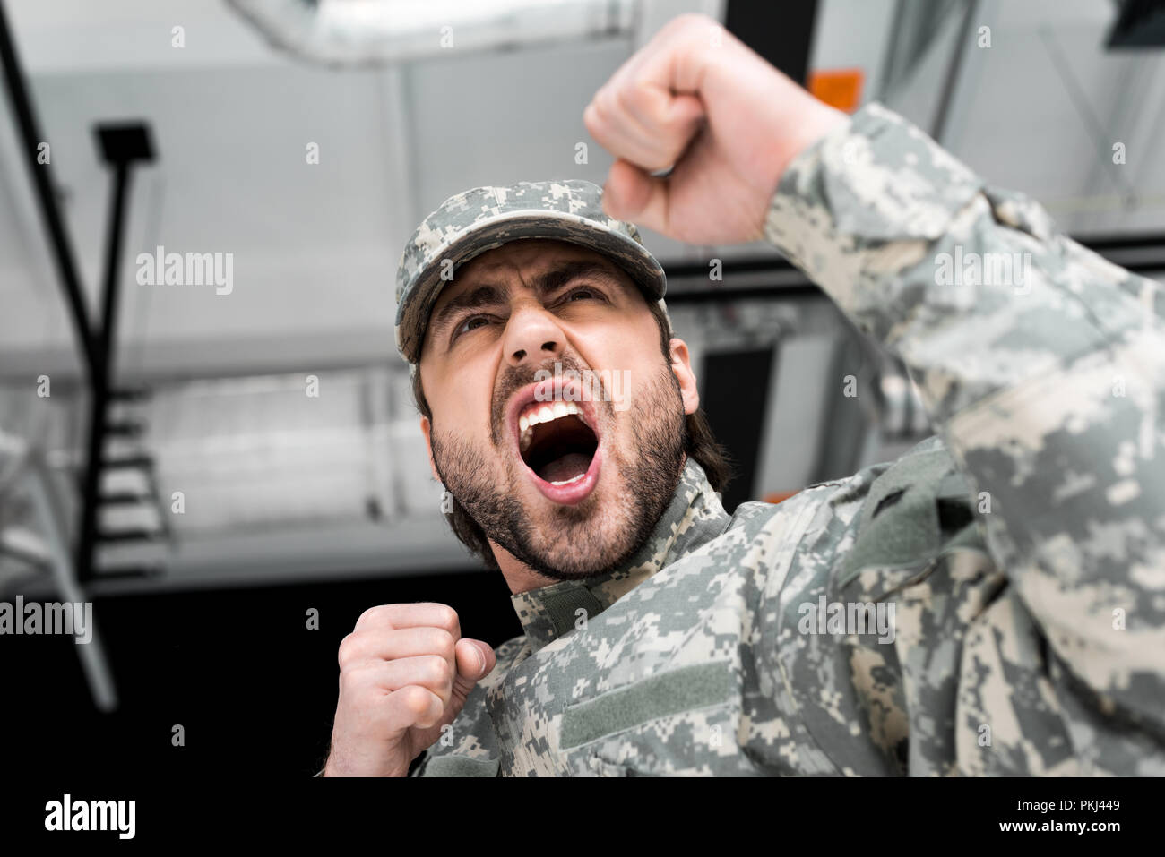 low angle view of emotional soldier in military uniform with blurred ...