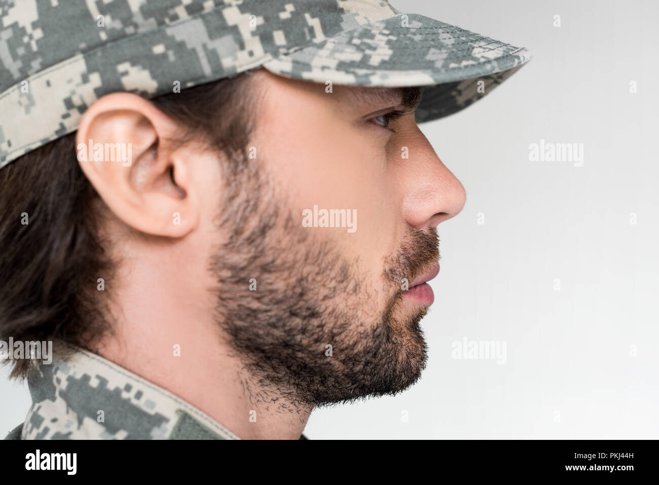side view of confident bearded soldier in military uniform looking away ...
