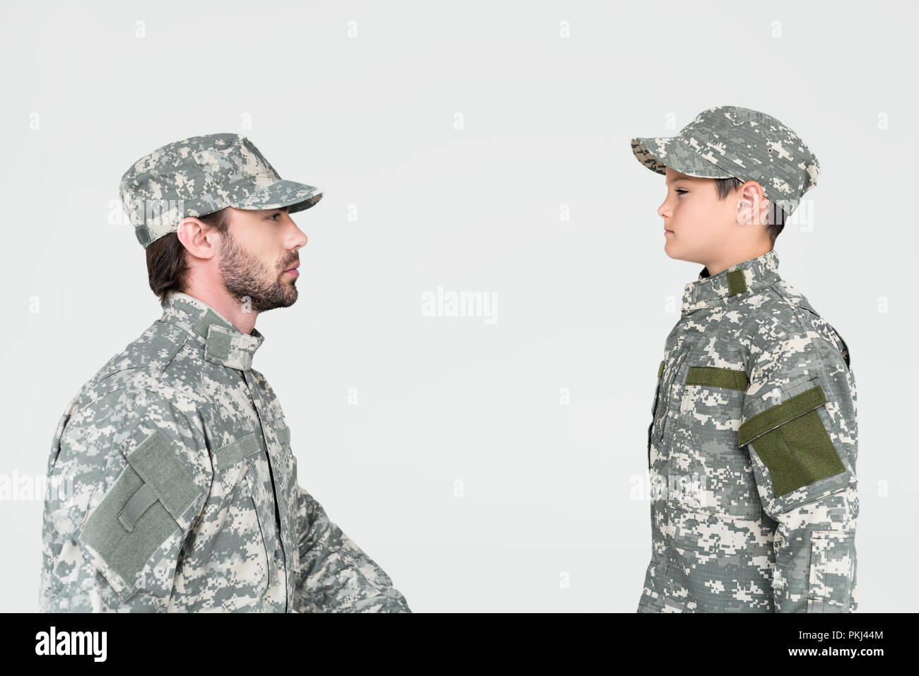side view of soldier and son in military uniforms looking at each other ...