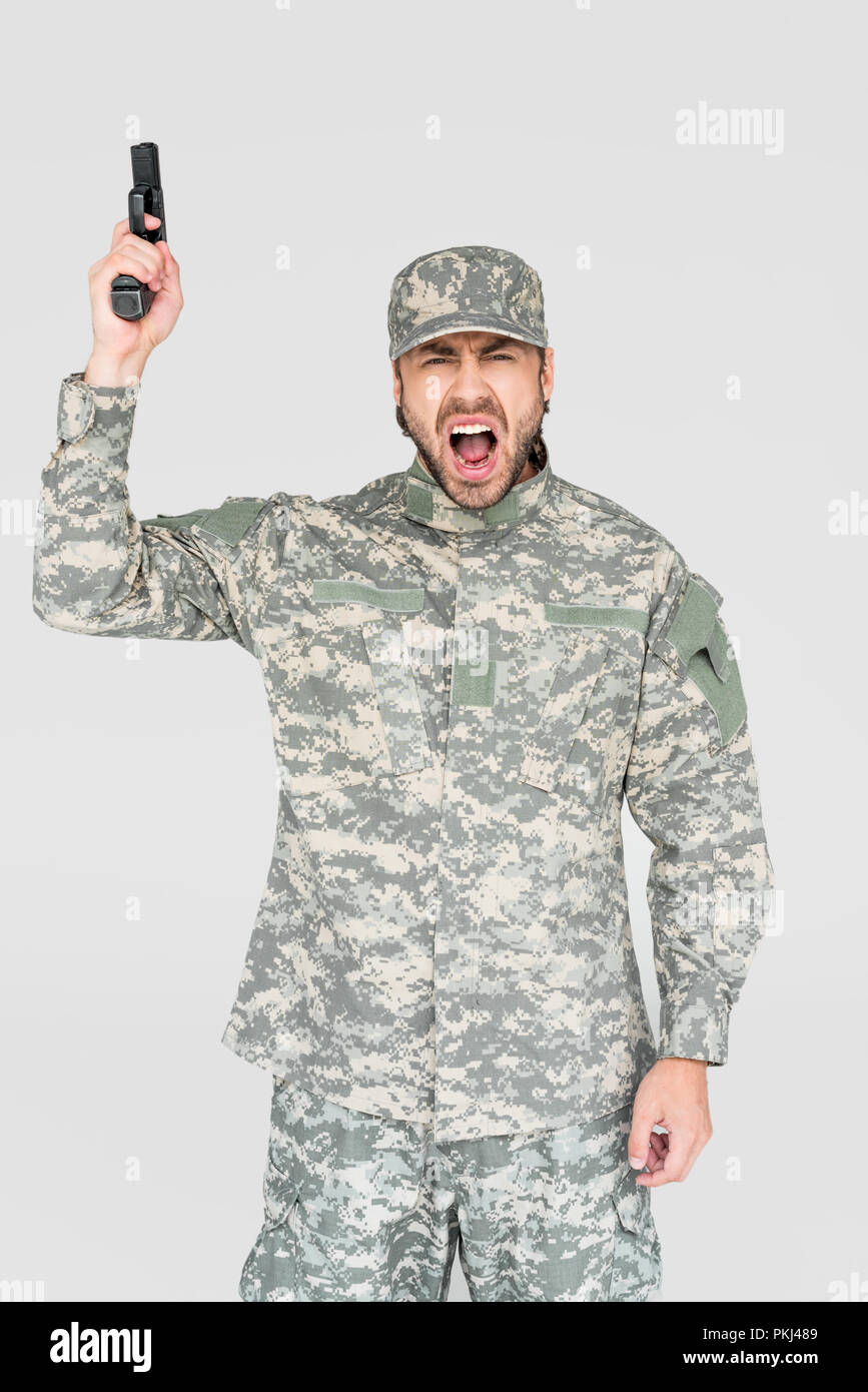 screaming male soldier in military uniform holding gun isolated on grey ...