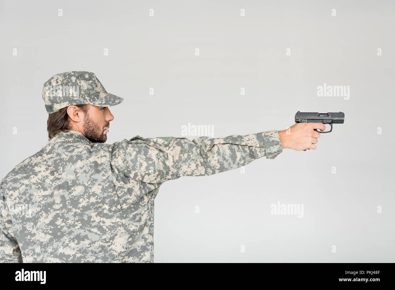 side view of male soldier in military uniform holding gun isolated on ...
