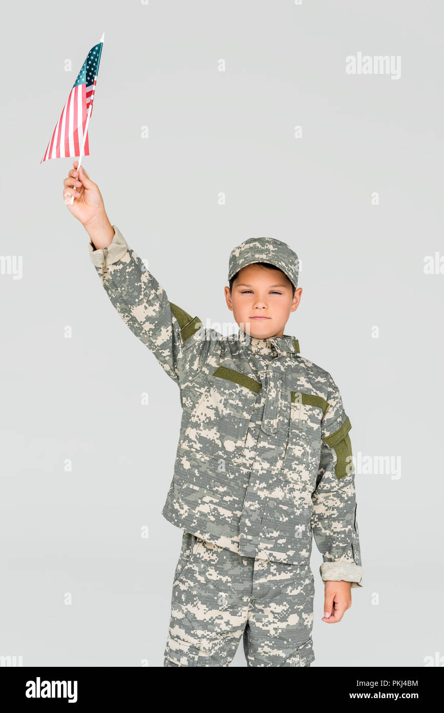 portrait of little boy in camouflage clothing holding american flagpole ...