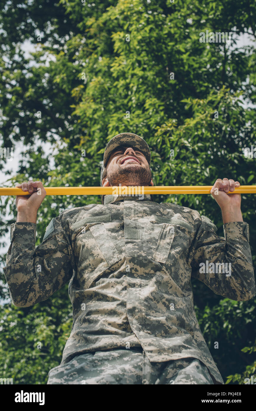 low angle view of soldier in military uniform pulling himself up on ...