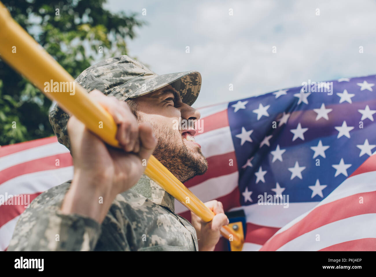 side view of soldier pulling himself up on crossbar with american flag ...