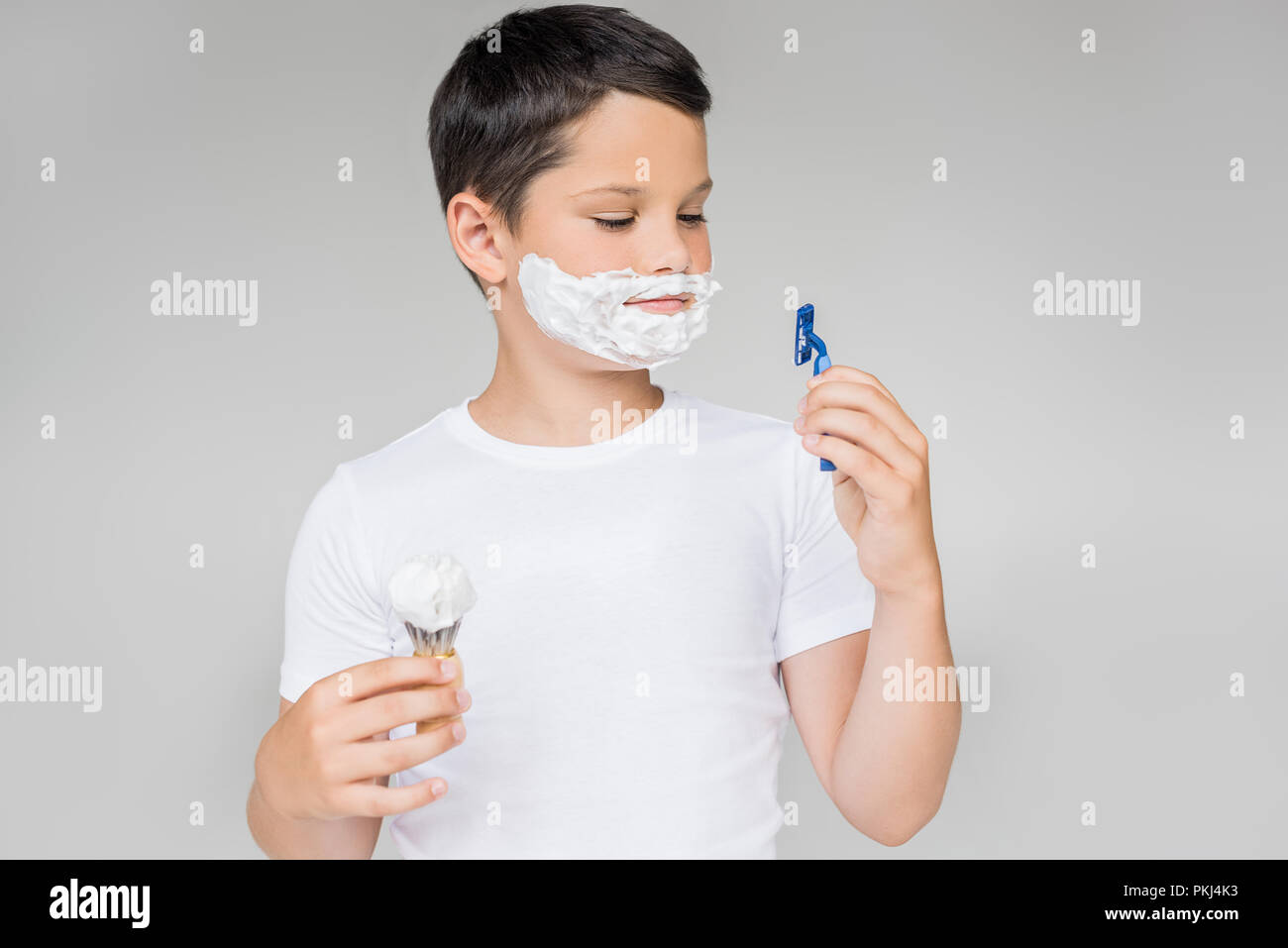 portrait of preteen boy with razor, brush shaving foam on face isolated ...