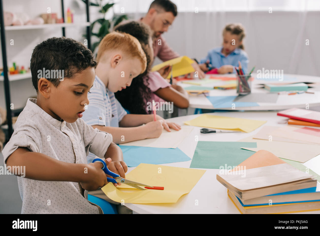 selective focus of teacher and interracial preschoolers cutting ...