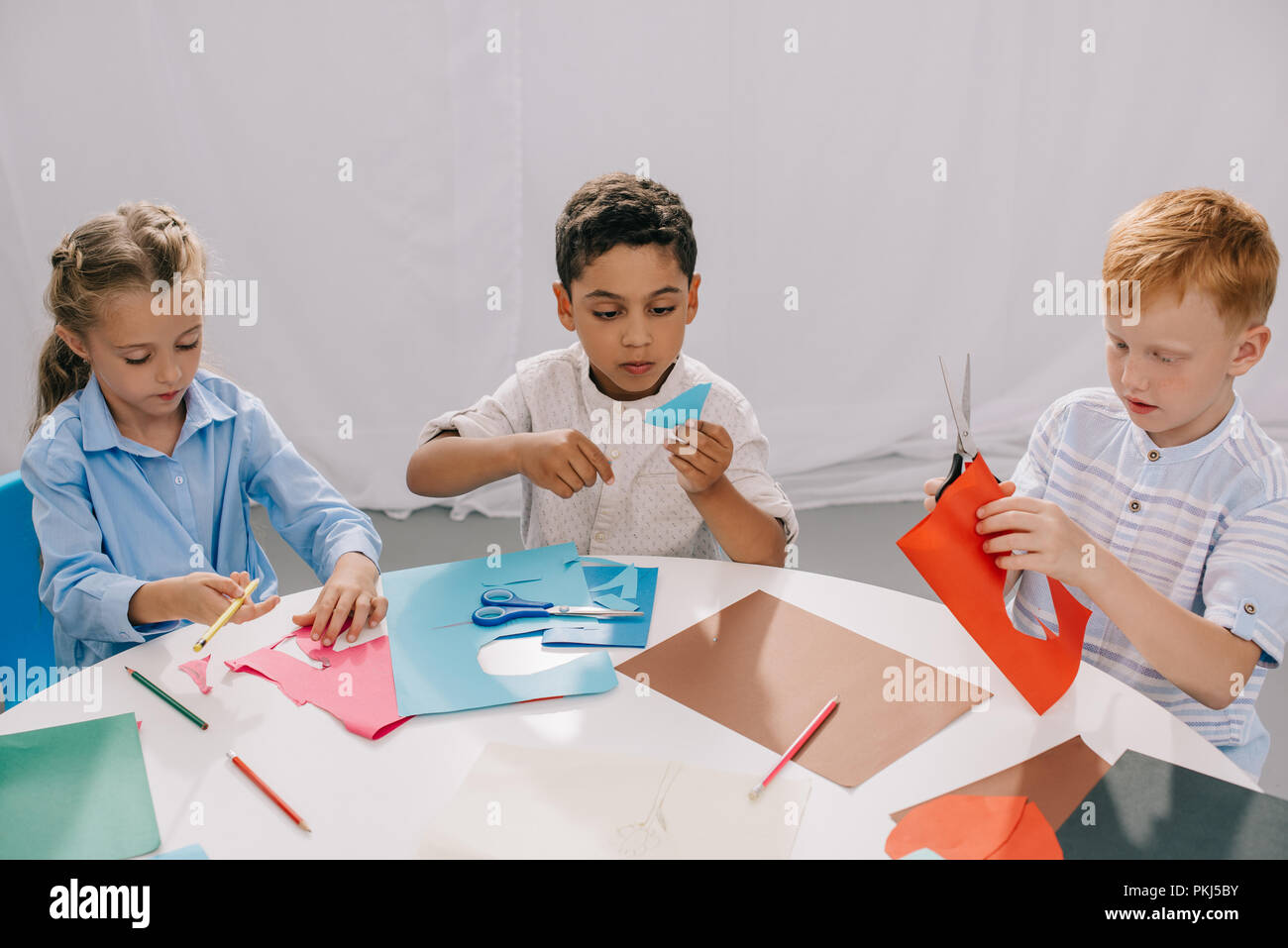 focused multiracial kids making paper applique in classroom Stock Photo ...