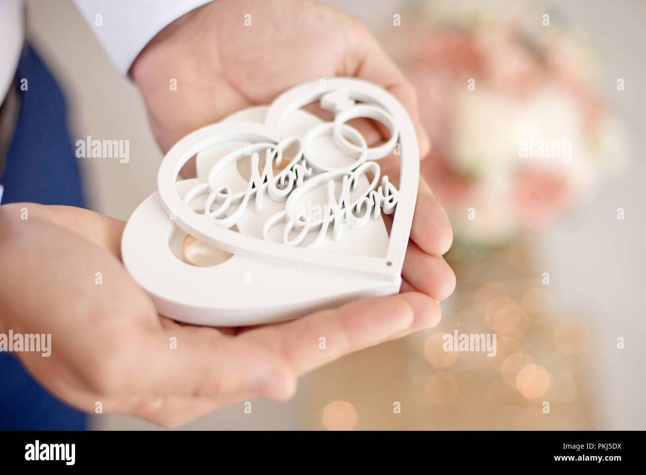 Close-up white handmade wedding gift box on male palms against blurred ...