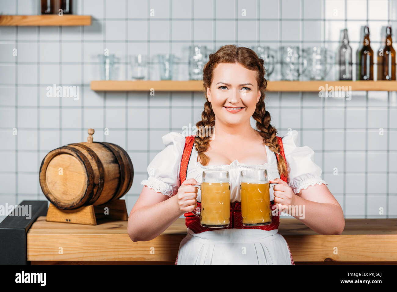 smiling oktoberfest waitress in traditional german dress holding mugs ...