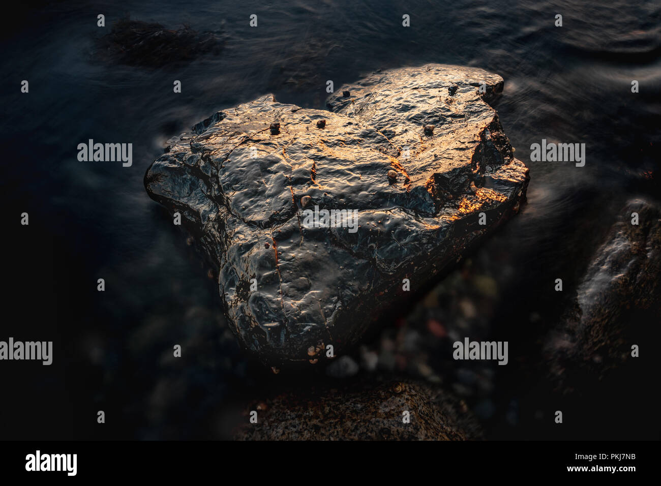 Rock in water and sunlight Stock Photo - Alamy