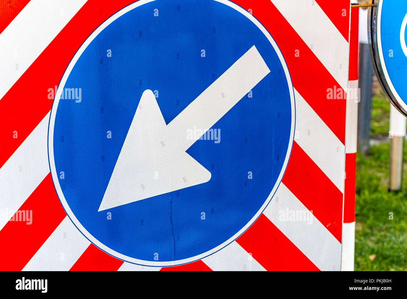 closeup of traffic arrow sign, white arrow on blue rounded road sign on ...