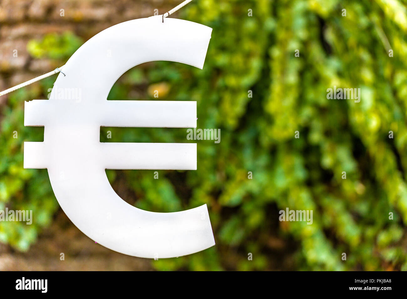 white euro sign hanging on green background Stock Photo - Alamy