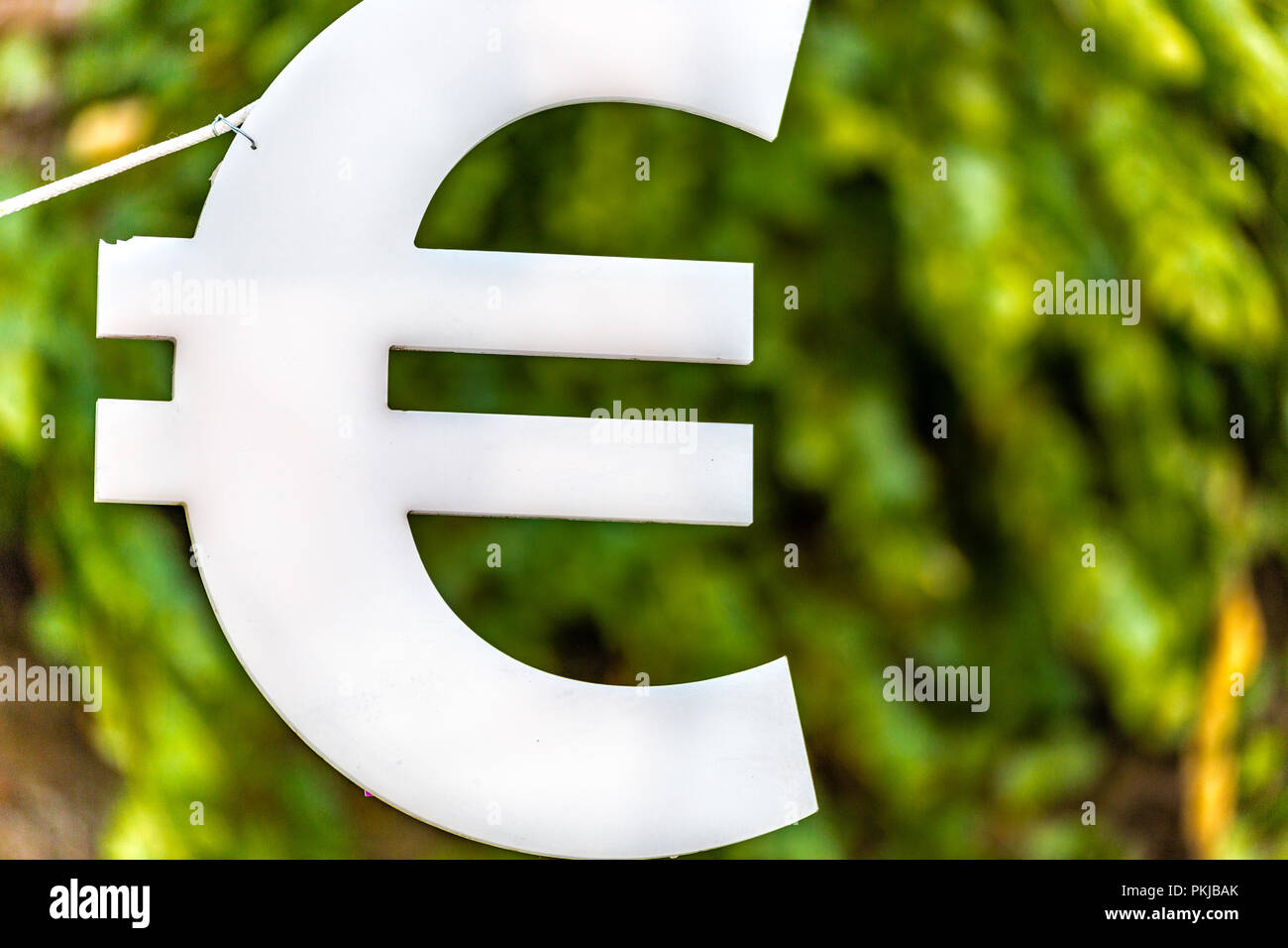 white euro sign hanging on green background Stock Photo - Alamy