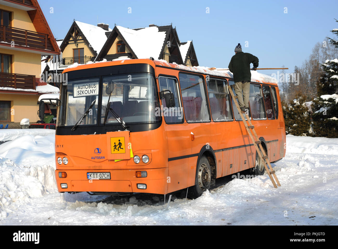 The driver of a school bus removes snow from the roof in Bialka ...