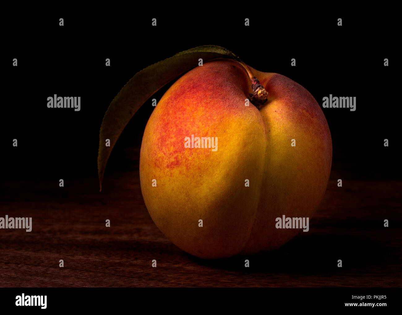Peach still life one fruit seen from the side against black background ...
