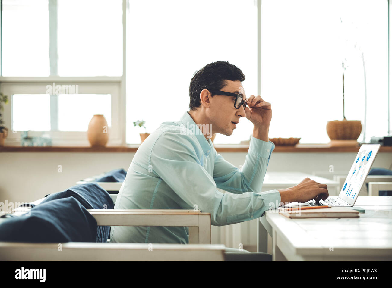 Serious smart man pressing a button on laptop Stock Photo - Alamy