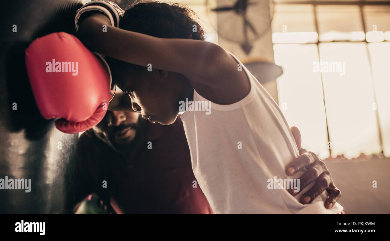 Boxing coach talking to a tired kid. Boxing kid relaxing after practice ...