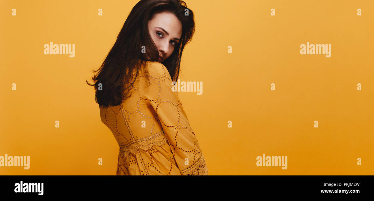 Portrait Of Attractive Female Model Glancing At Camera In Orange Dress