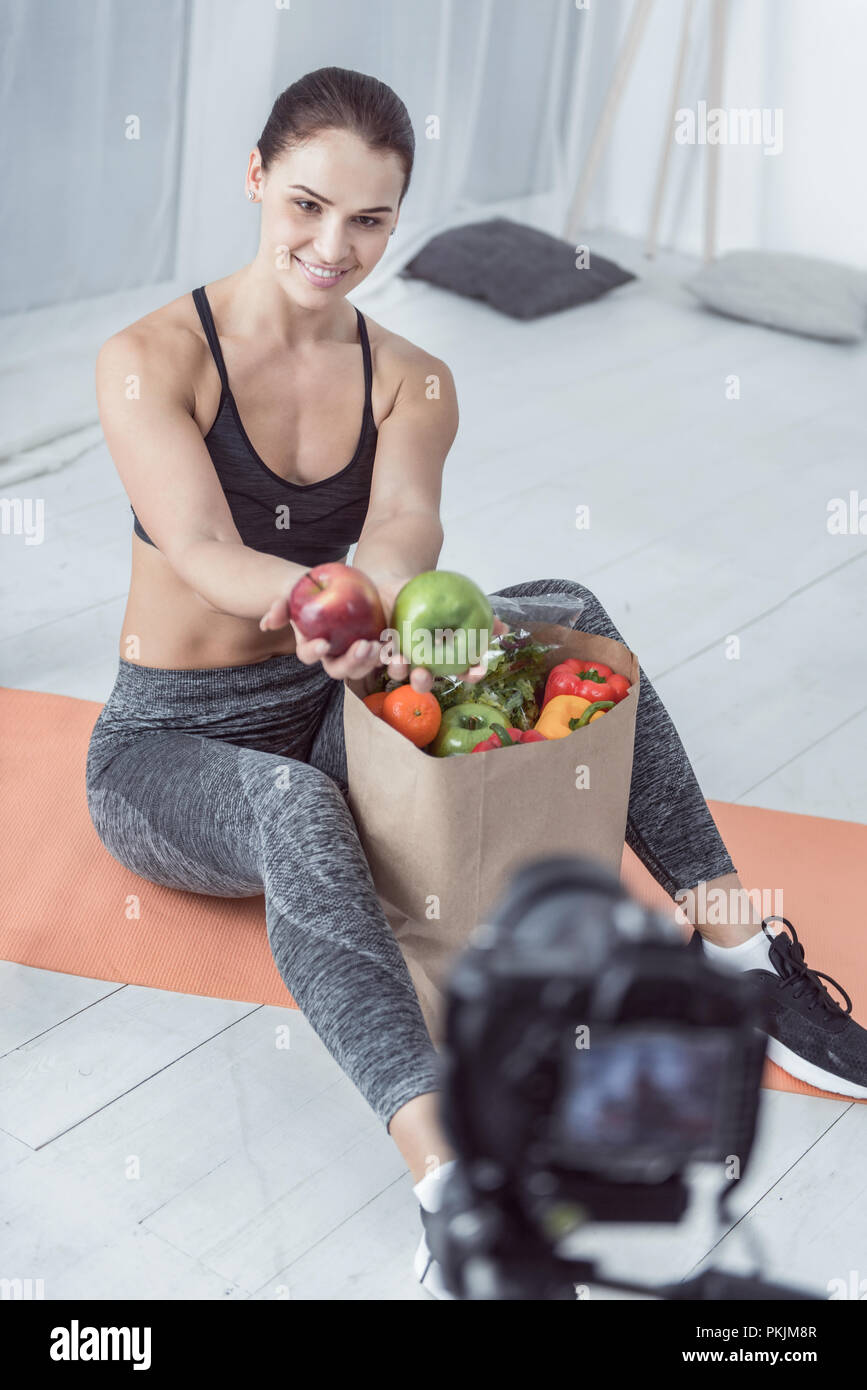 Positive fit woman showing apples to her viewers Stock Photo - Alamy