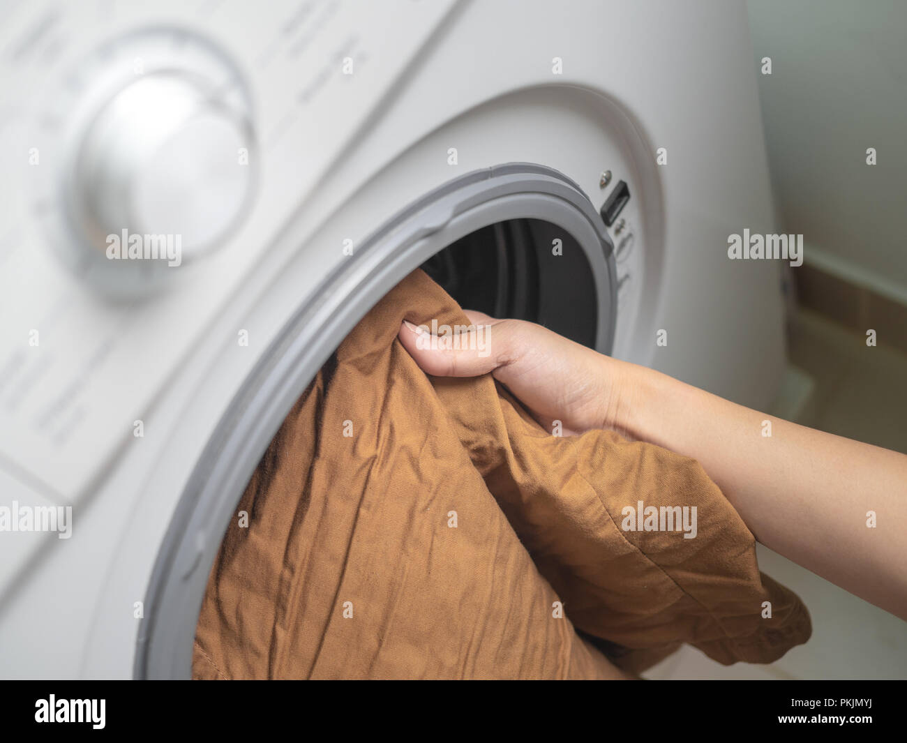 Close up hand putting dirty shorts in washing machine Stock Photo - Alamy