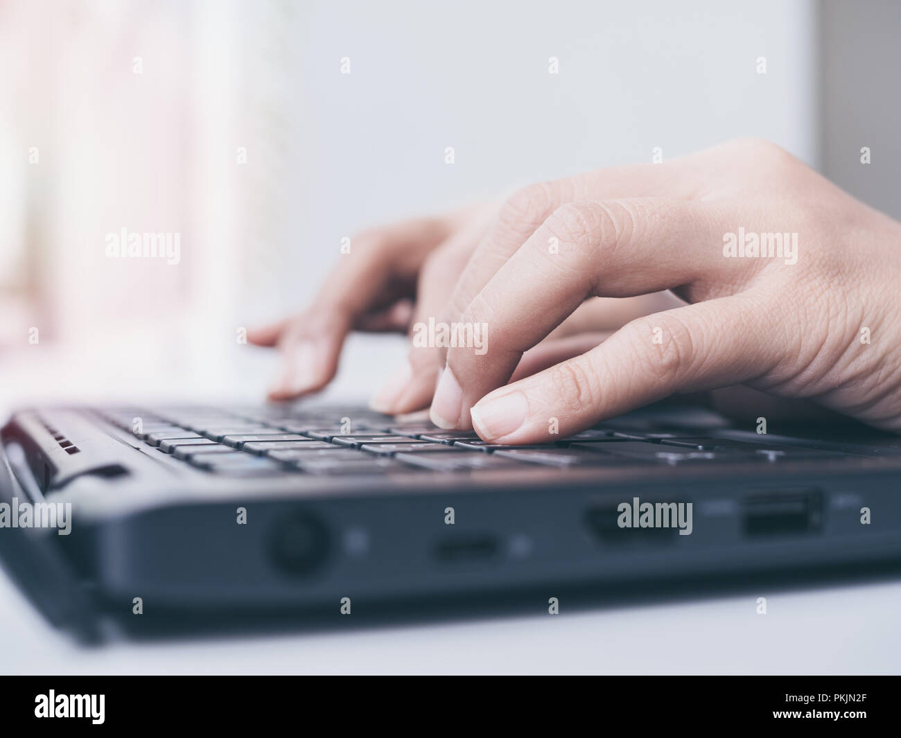 Closeup hands typing on black laptop computer keyboard on white table ...