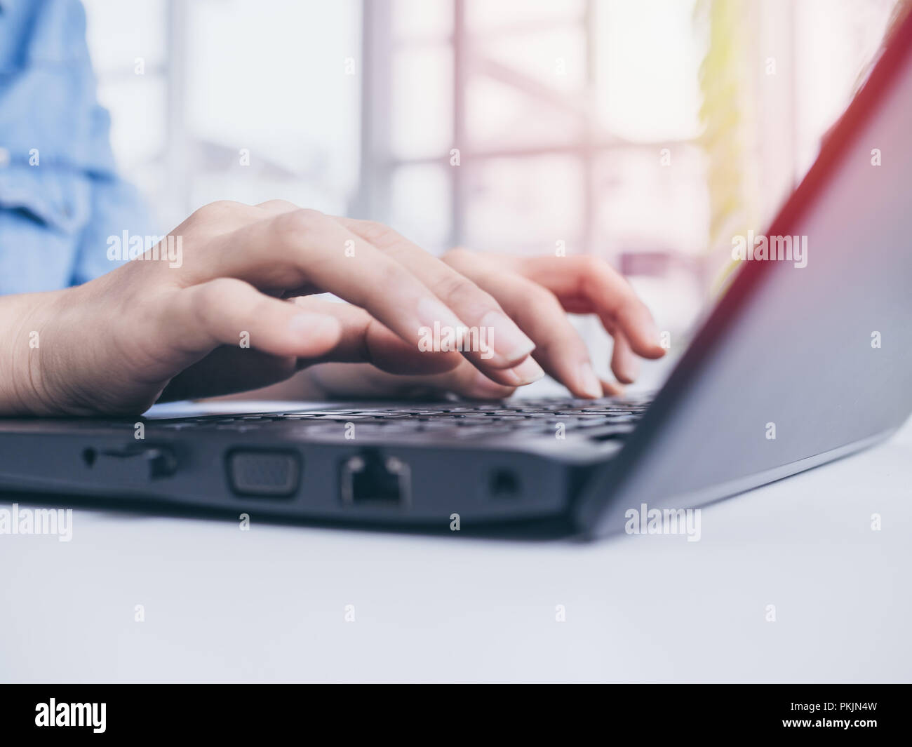 Close-up hands typing on black laptop computer keyboard on white table ...