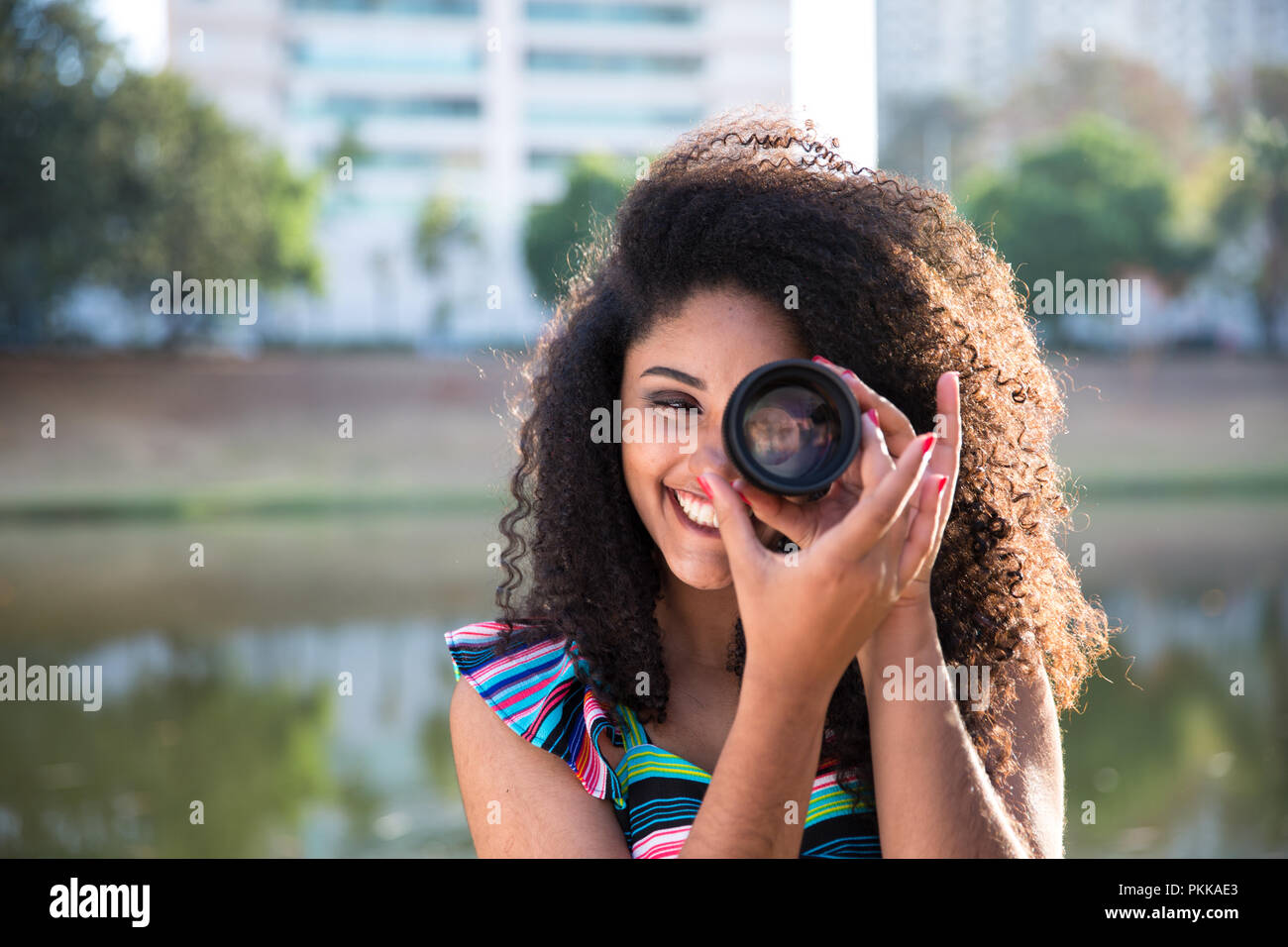Black woman holding a camera len outside Stock Photo - Alamy