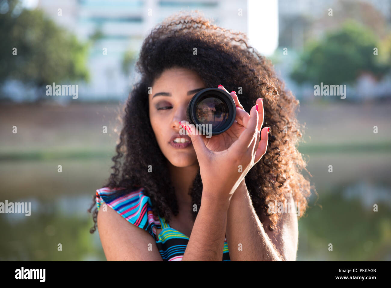 Black woman holding a camera len outside Stock Photo - Alamy