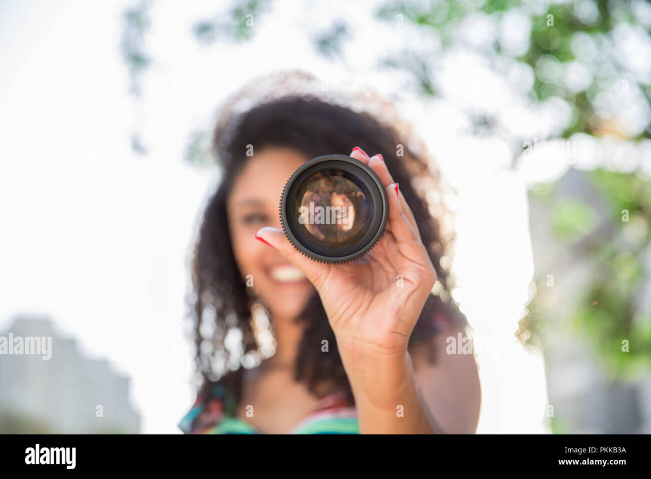 Black woman holding a camera len outside Stock Photo - Alamy