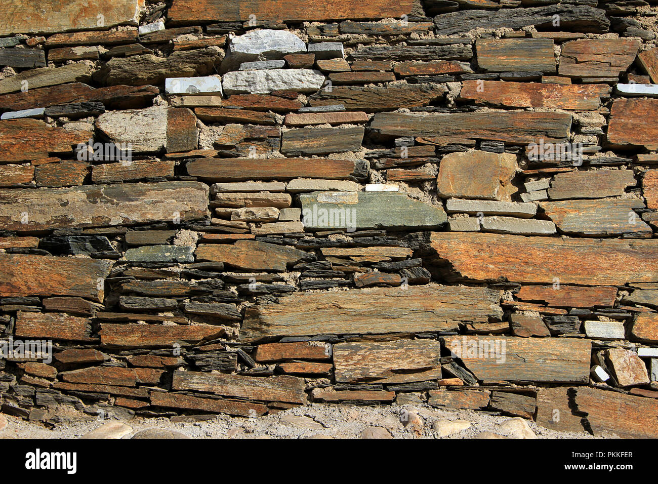Wall built up of neatly laid out layers of flat stone blocks with ...