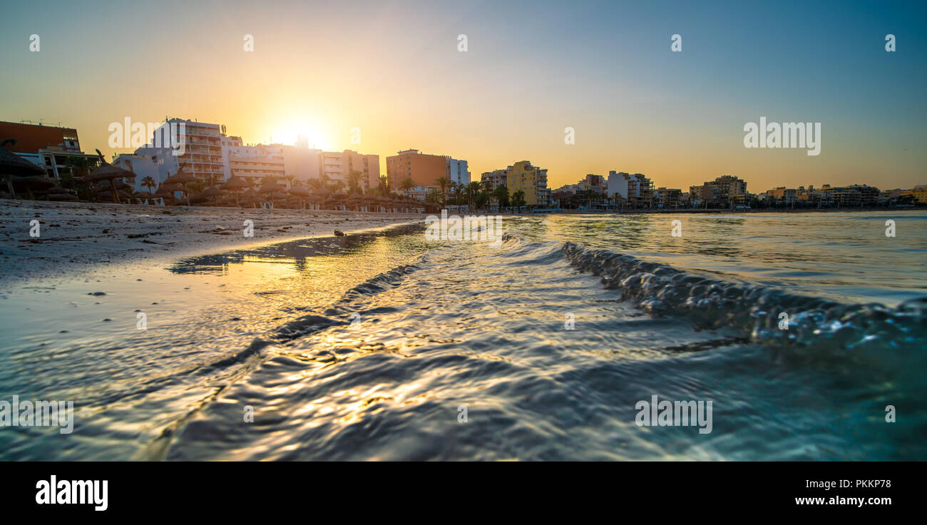 Wavy curves of sea is covered in golden sunset light. Sea at sunset ...