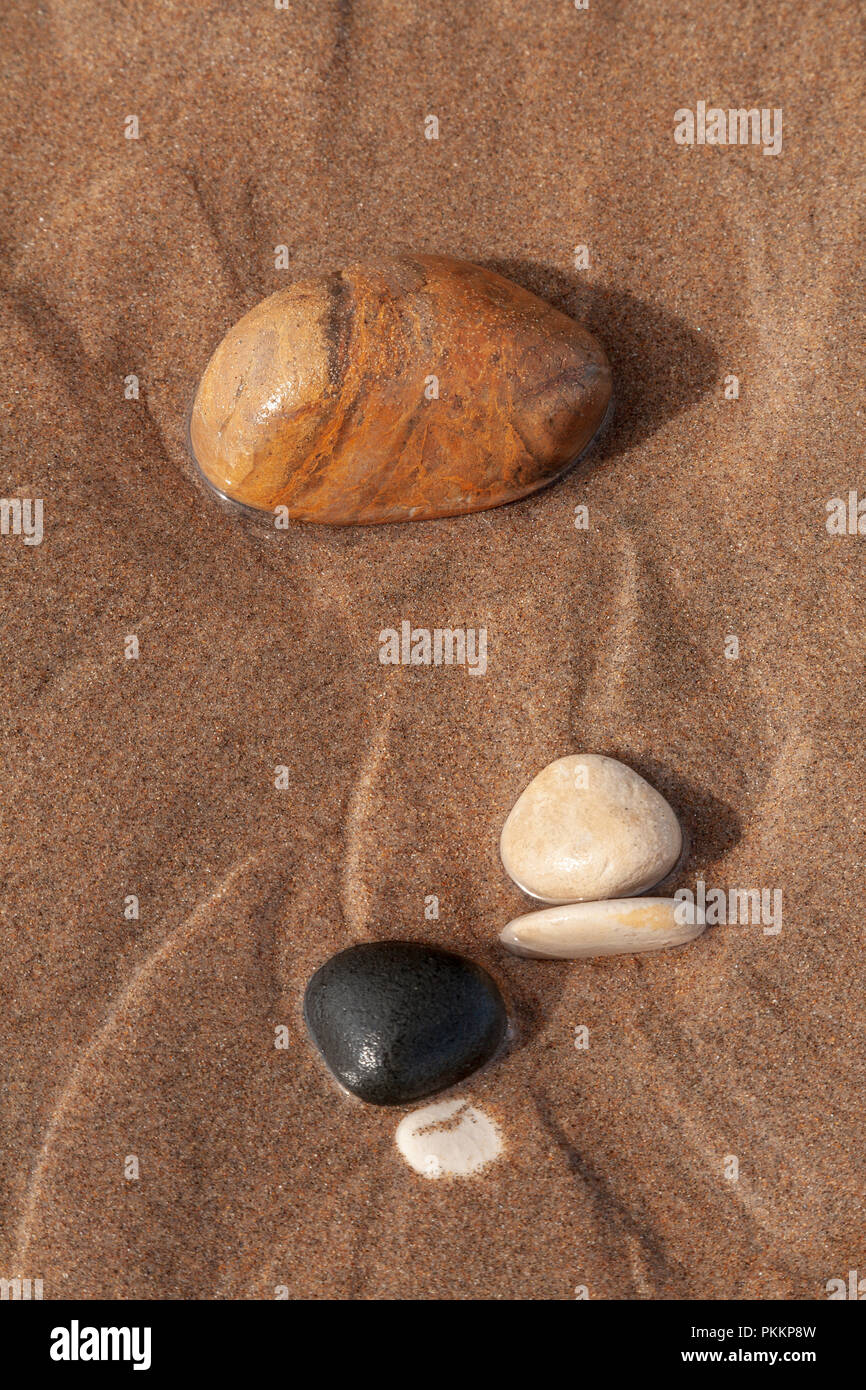 Smooth wet stones in the sand on the Antrim coast at Whitepark Bay ...